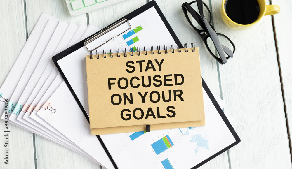 STAY FOCUSED ON THE END GOAL notepad writing concept on dark background ...