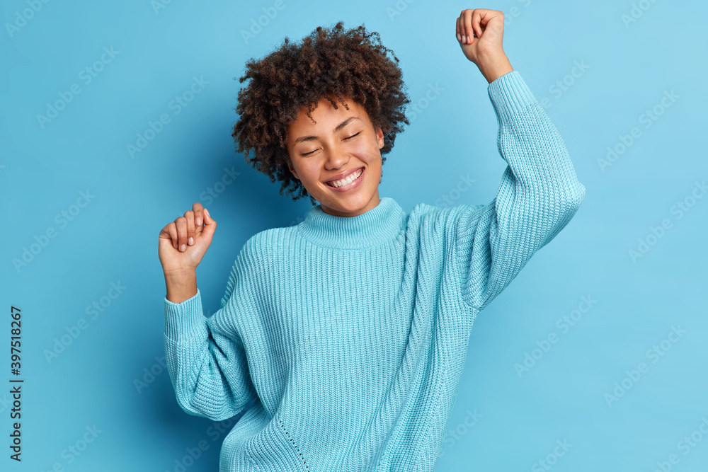 Foto de Joyful carefree woman poses full of happiness raises arms and ...