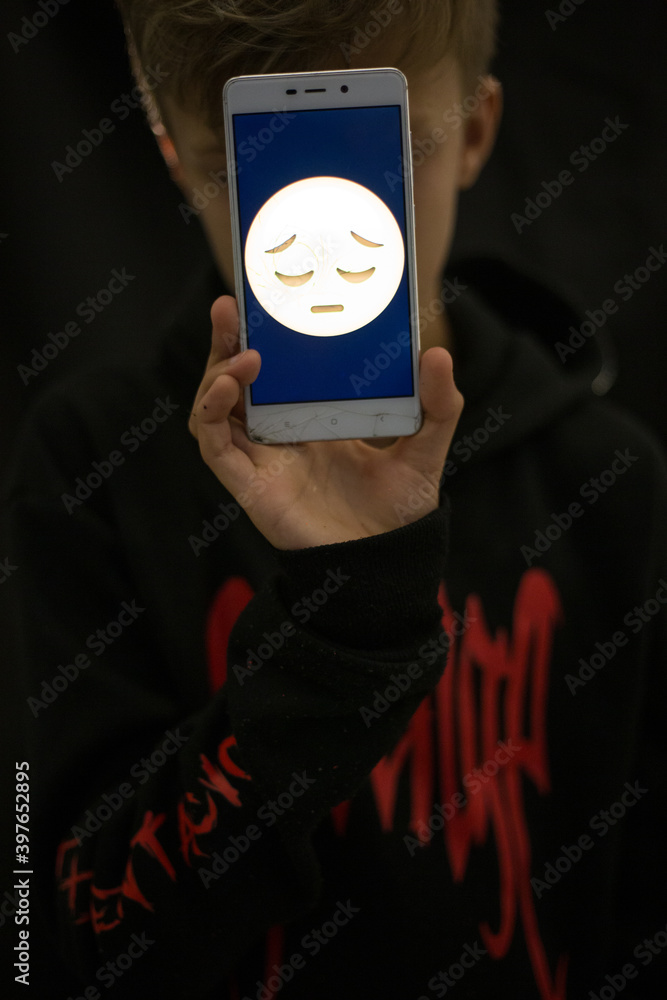 Sad emoji on the phone screen in the hands of a boy Stock Photo | Adobe ...