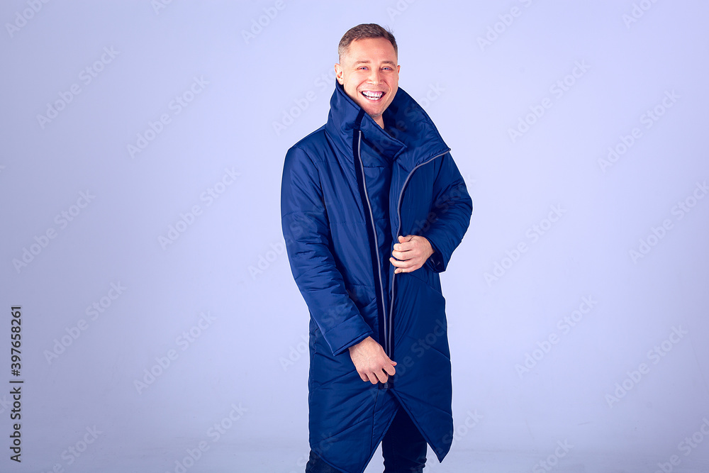 sincere laugh of a young man on a gray background. Dressed in a warm ...