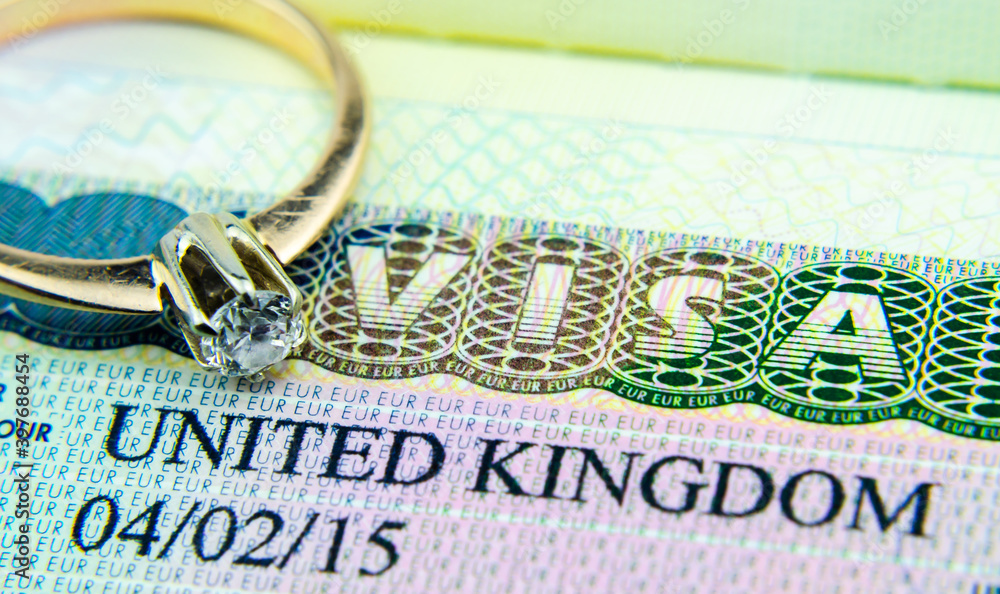 UK entry visa sticker in a passport and the engagement ring placed on ...