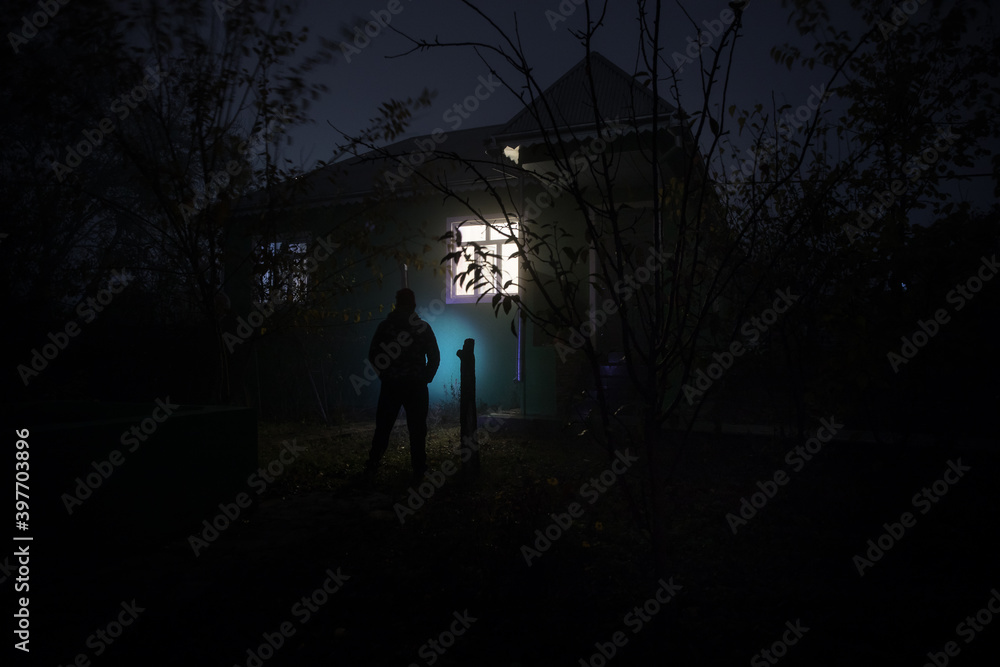 Old house with a Ghost in the forest at night. Horror silhouette at the ...