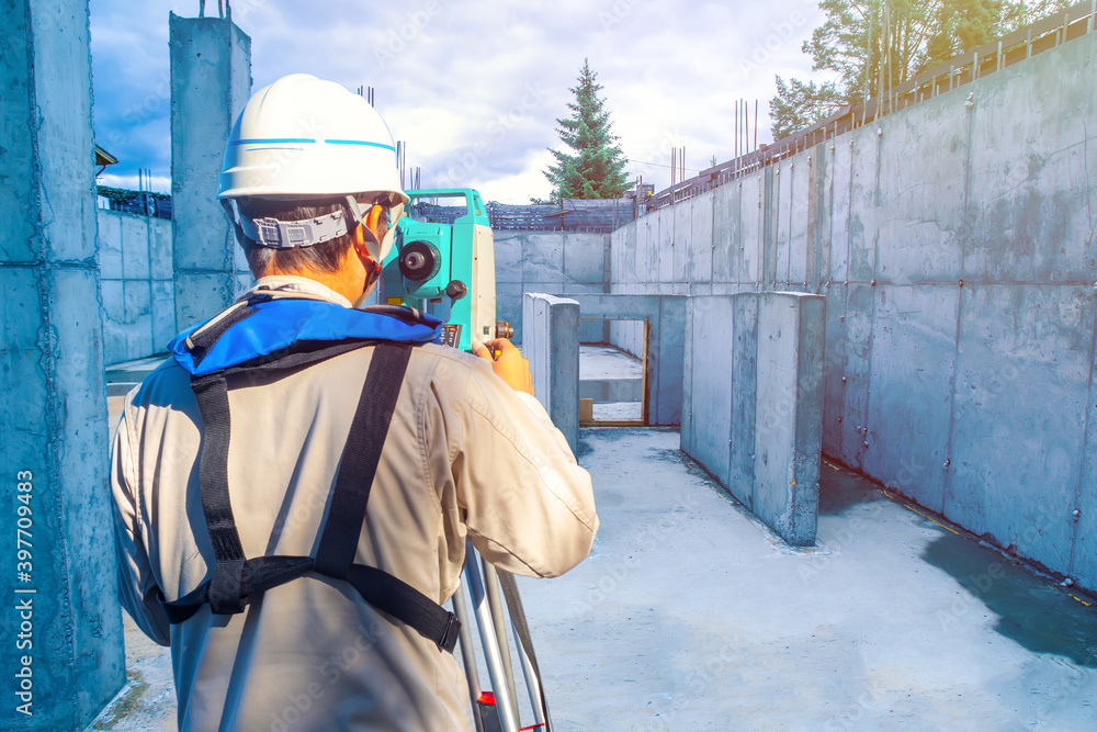 Surveyor inside a building under construction. Man with a tachometer at ...