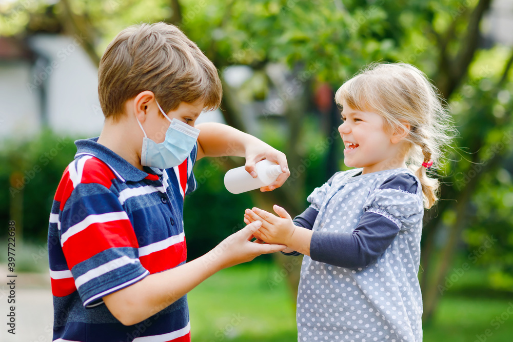 School kid boy helping little toddler sister cleaning hands with ...