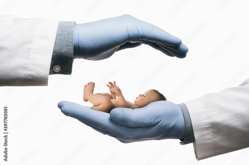 Baby between two palms of doctor hands on white isolated background. In ...