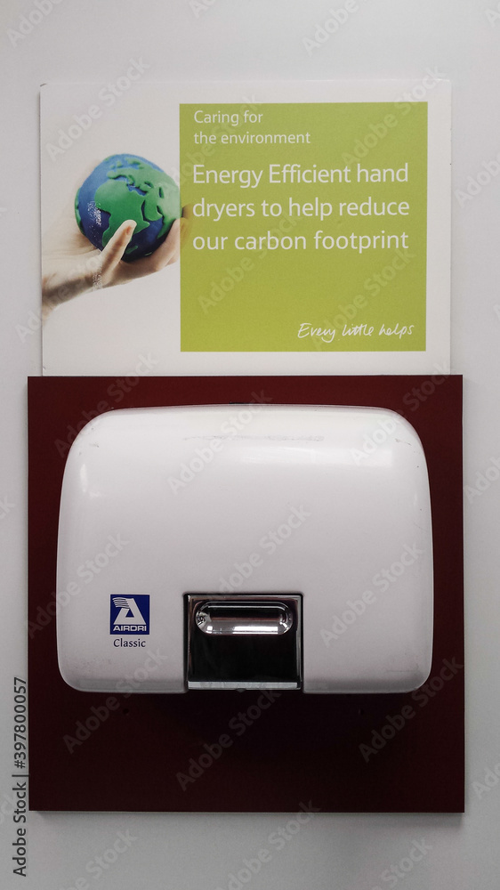 Hot air hand dryer on a wall with an evironmentally friendly sign above ...