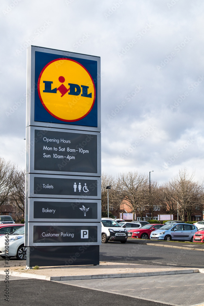 Lidl sign at entrance to customer car park. Displays opening hours and ...