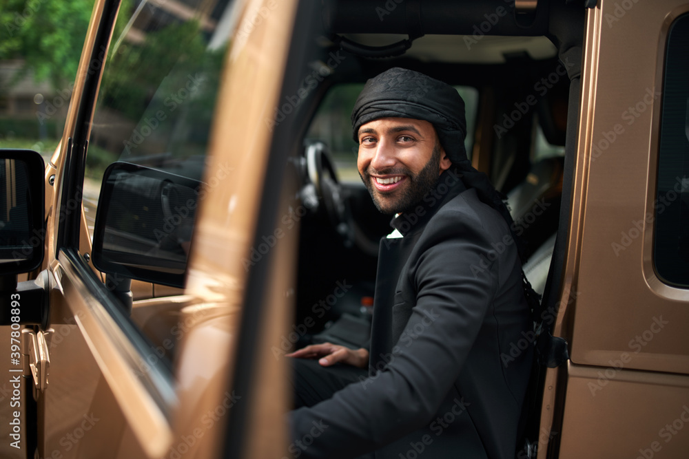 Arab man getting into luxury vehicle wearing traditional suite with ...