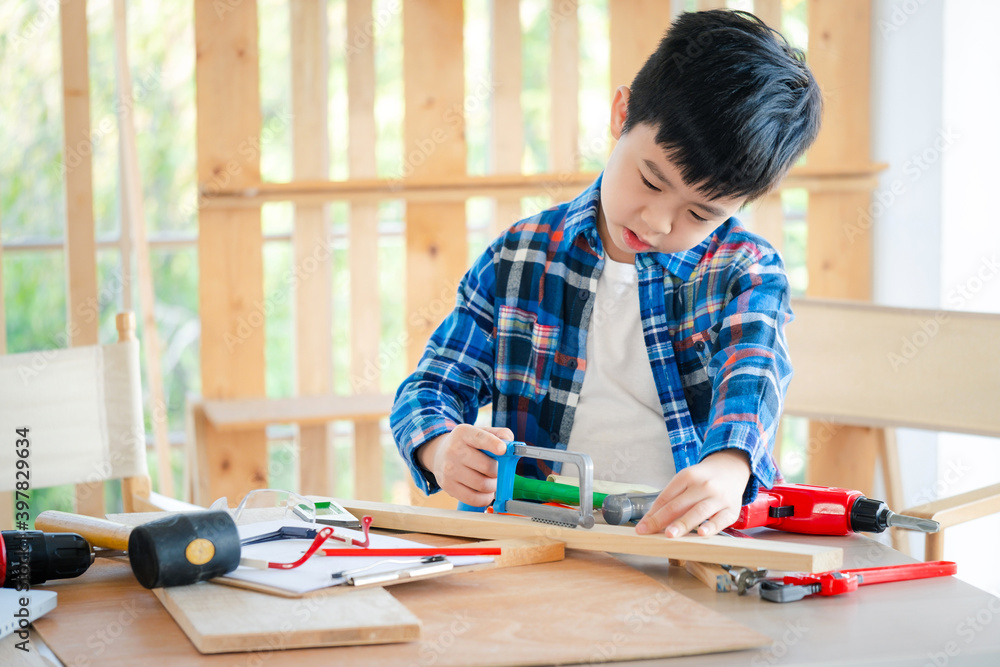 Young Asia boy wearing a shirt and concentrate sawing wood with a toy ...