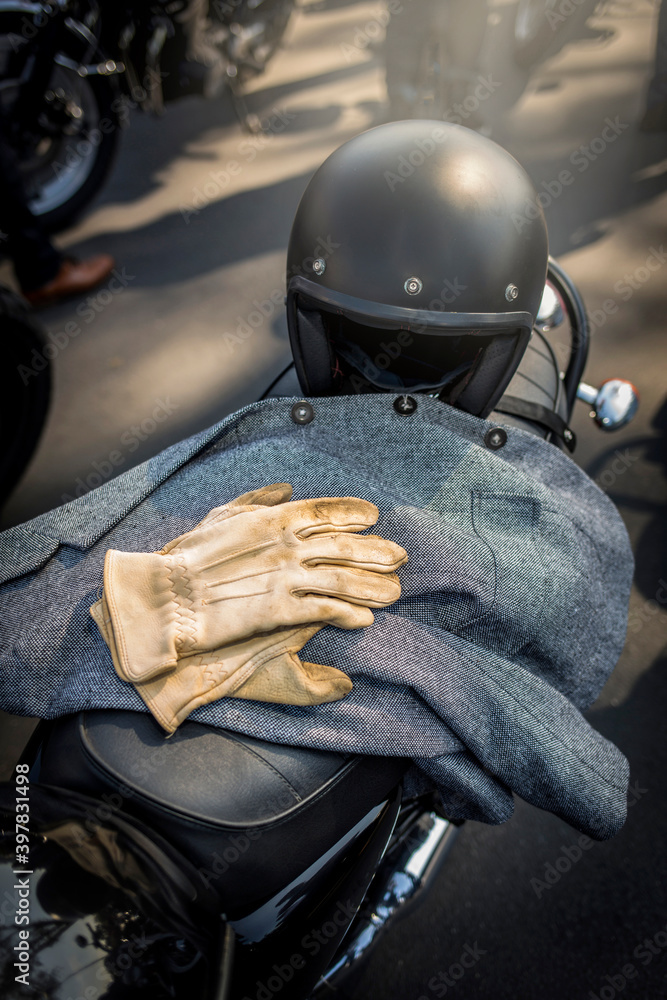 Vintage tweed jacket , leather gloves,helmet, resting on street ...