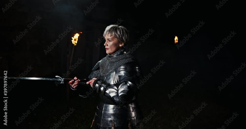 Medieval female knight raising sword in darkness. Joan of Arc ...