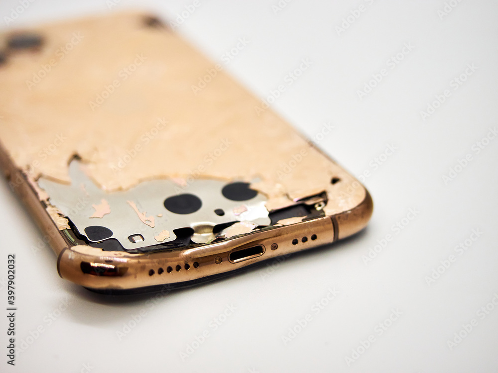 The back of modern gold smartphone with a broken glass and a damaged ...