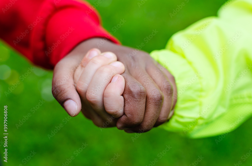 Two children of different races holding hands together. Photo shows ...