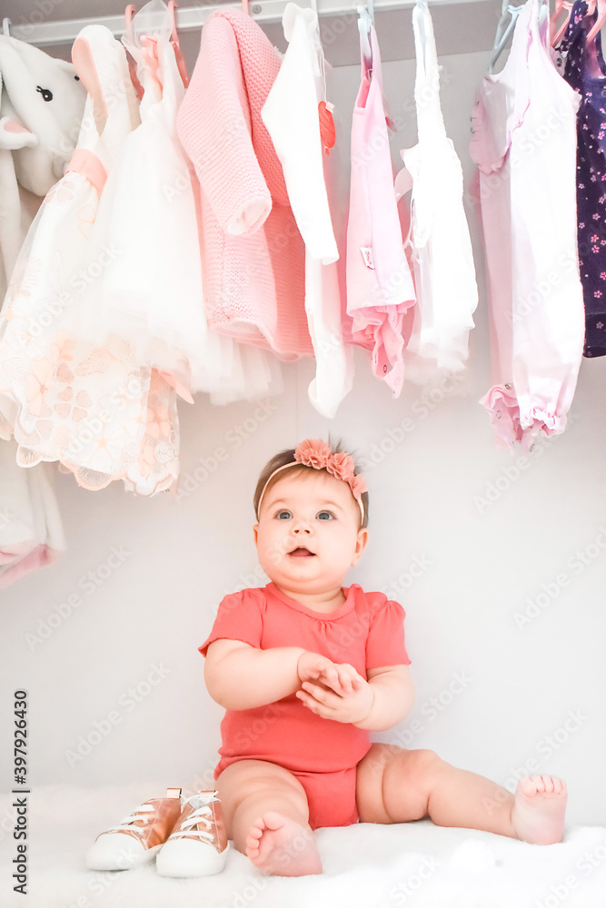 Pretty cute little baby girl sitting inside white wardrobe with clothes ...