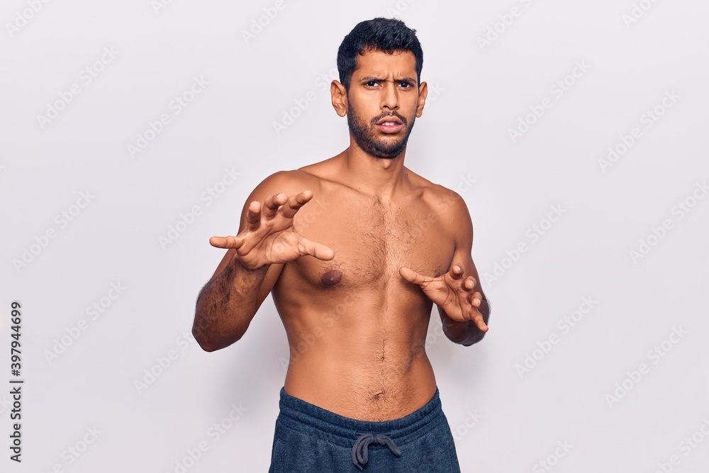 Young latin man standing shirtless disgusted expression, displeased and ...