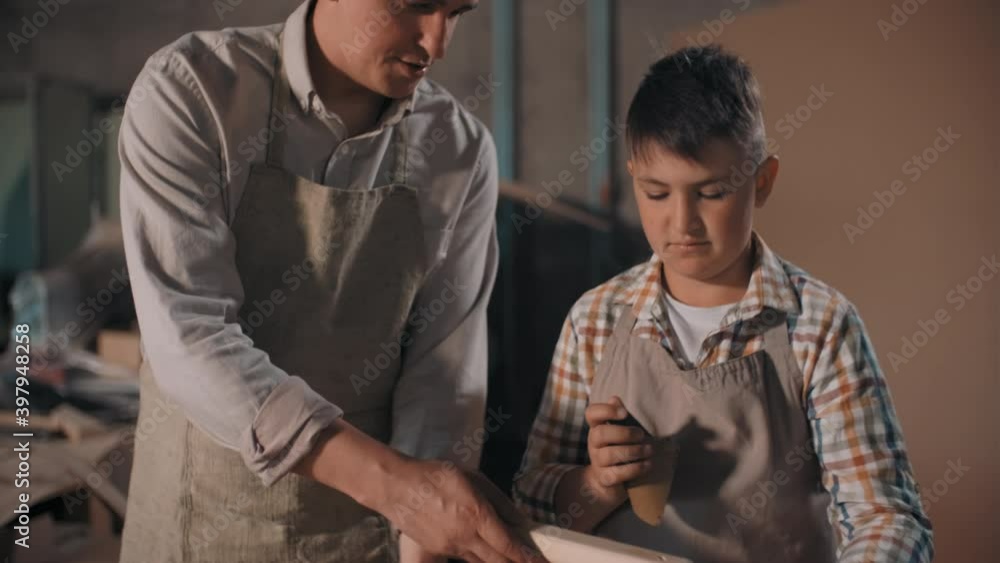 Tilting-up medium footage of little boy sanding wood with sandpaper ...