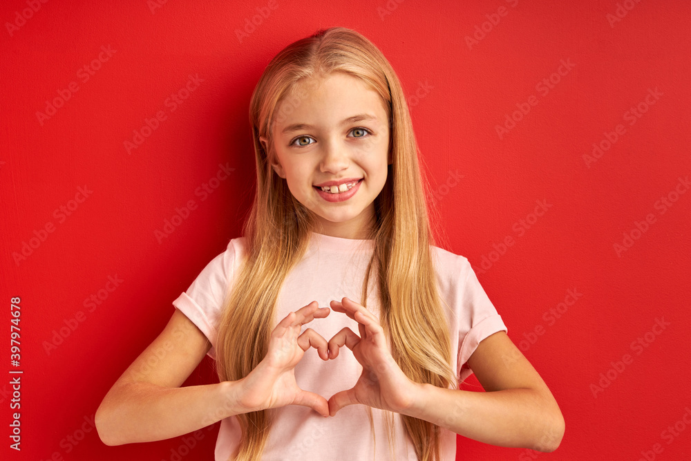 little child girl expresses love, make shape of love with fingers ...