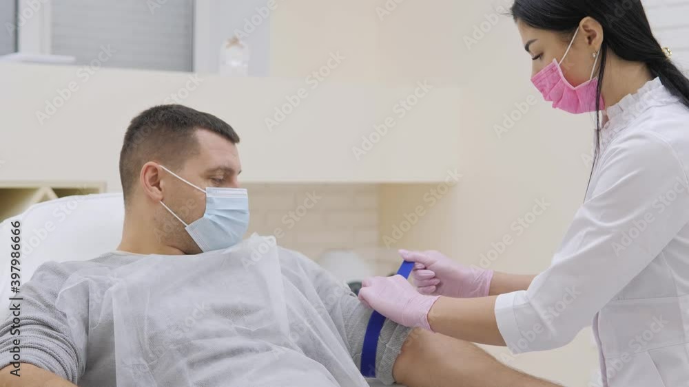 Young female doctor injecting male patient with syringe to collect ...