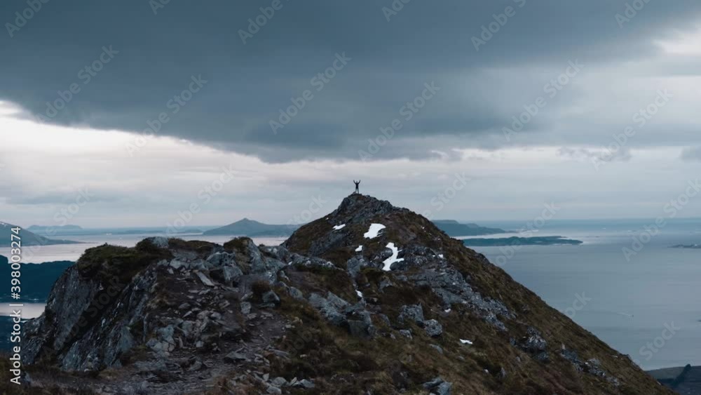 Camera zooming out from a small person standing with arms up in the air ...