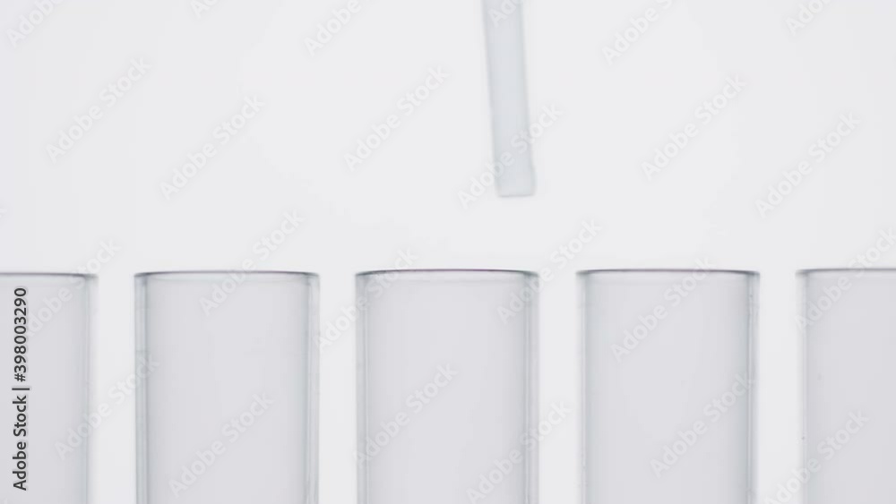 Pipette dropping sample into test tube at white background. Medical ...