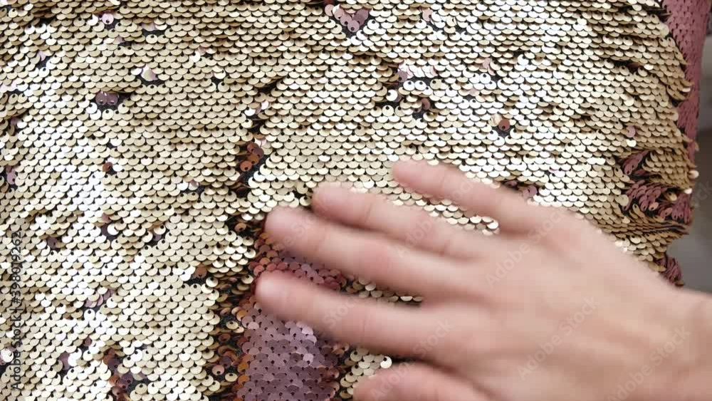 The hand stroking round golden sequins close up Hand Touches a shiny ...
