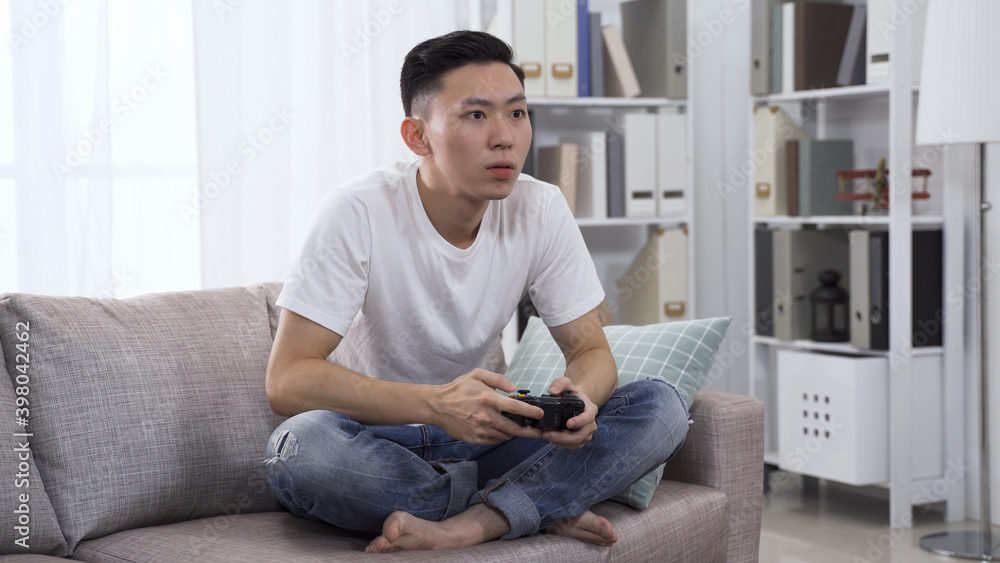 handsome asian man holding wireless controller is playing video game in ...