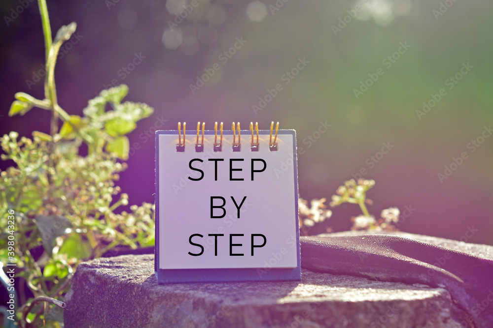 Step by step text written on note with blurred background of hanging ...
