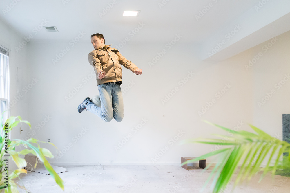 Skilled young man jumping up performing mid-air trick with soccer ball ...