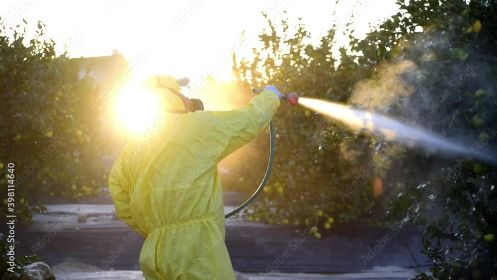Farmer in protective clothes spray pesticides. Farm worker spray ...