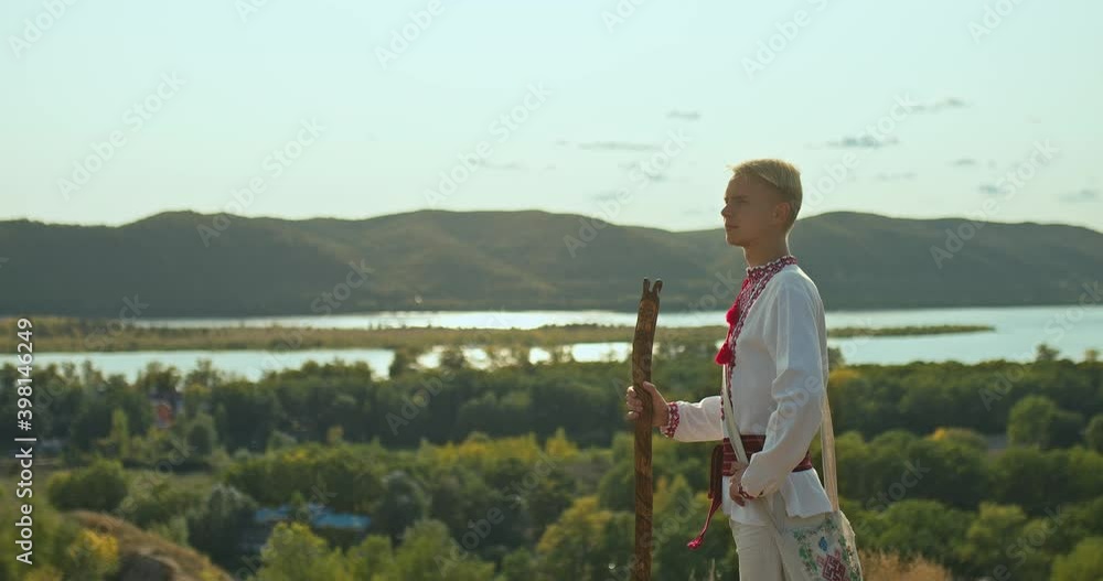 Portrait, a handsome man stands on a mountain with a staff and looks ...