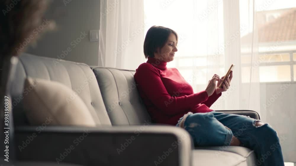 Relaxed young woman using her smartphone surfing social media, checking ...