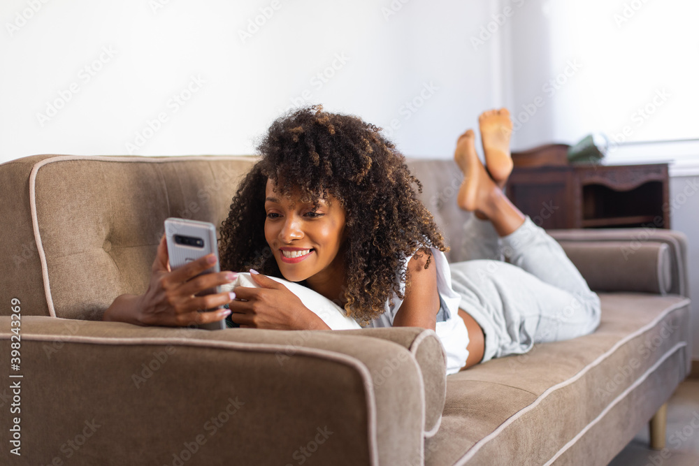 Relaxed cheerful black woman at home lying on her couch at home and ...