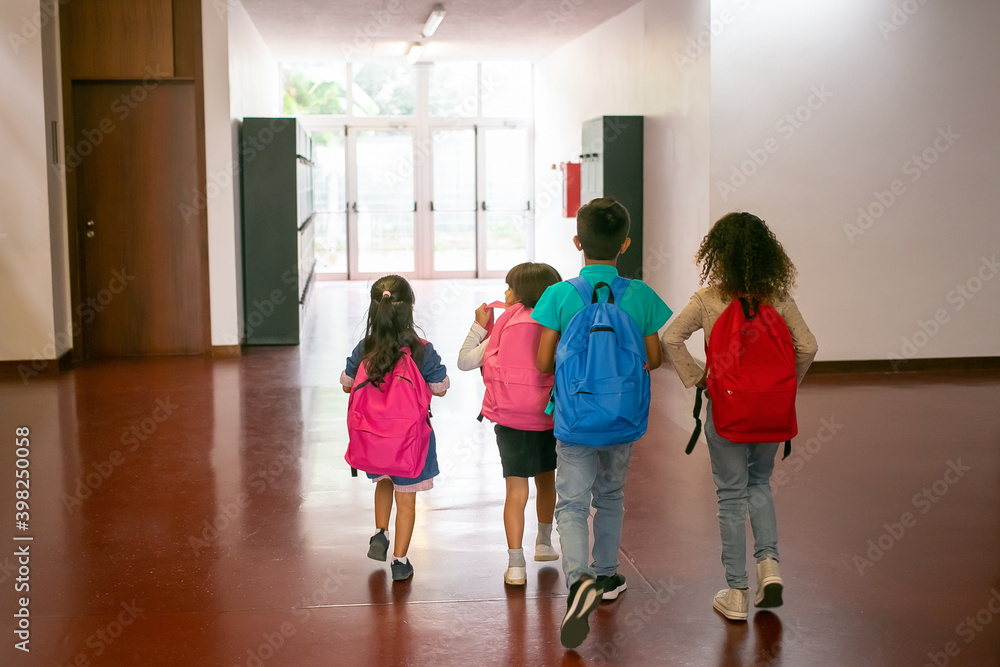 Group of children with colorful backpacks walking in school corridor to ...