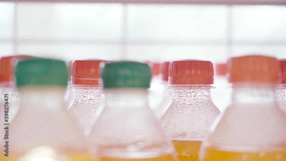 Lots of Plastic Drinks Bottles in the Shop by the Window. Orange and Green Bottle Caps.CLOSE-UP ...