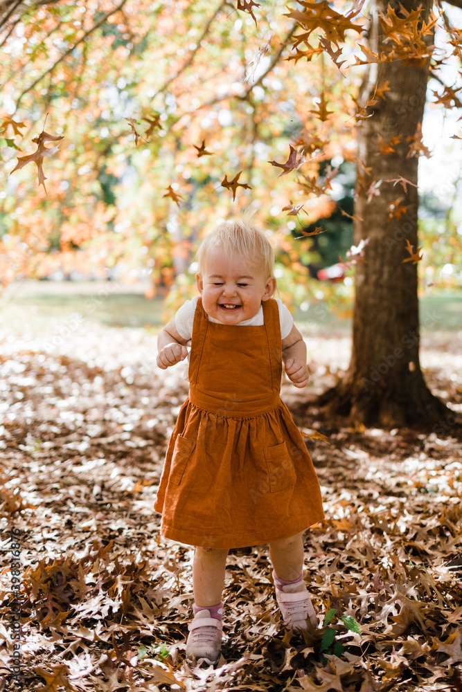 little girl scrunches up face in happiness as leaves fall Stock Photo ...