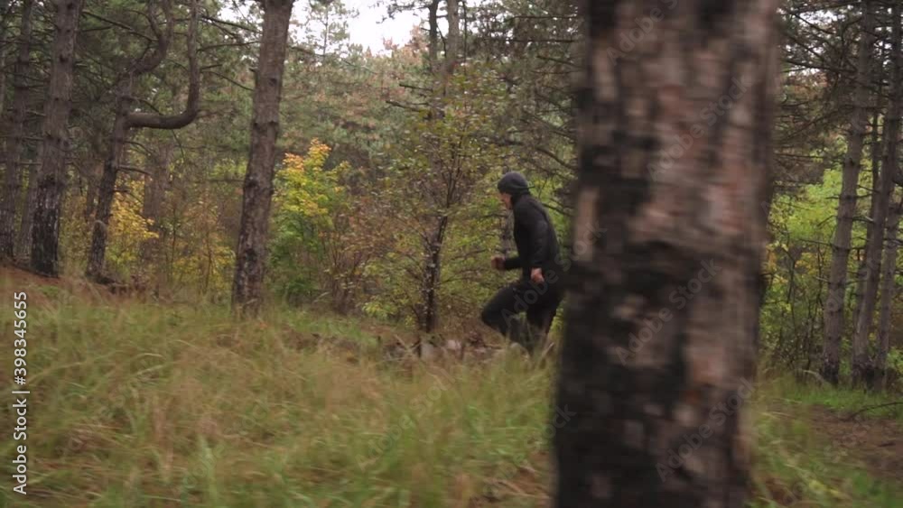 An athlete in black clothes, in a hat, runs quickly through a dark ...