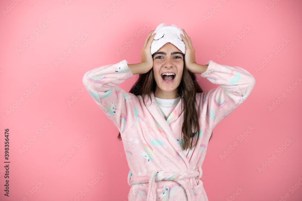 Pretty girl wearing pajamas and sleep mask over pink background ...