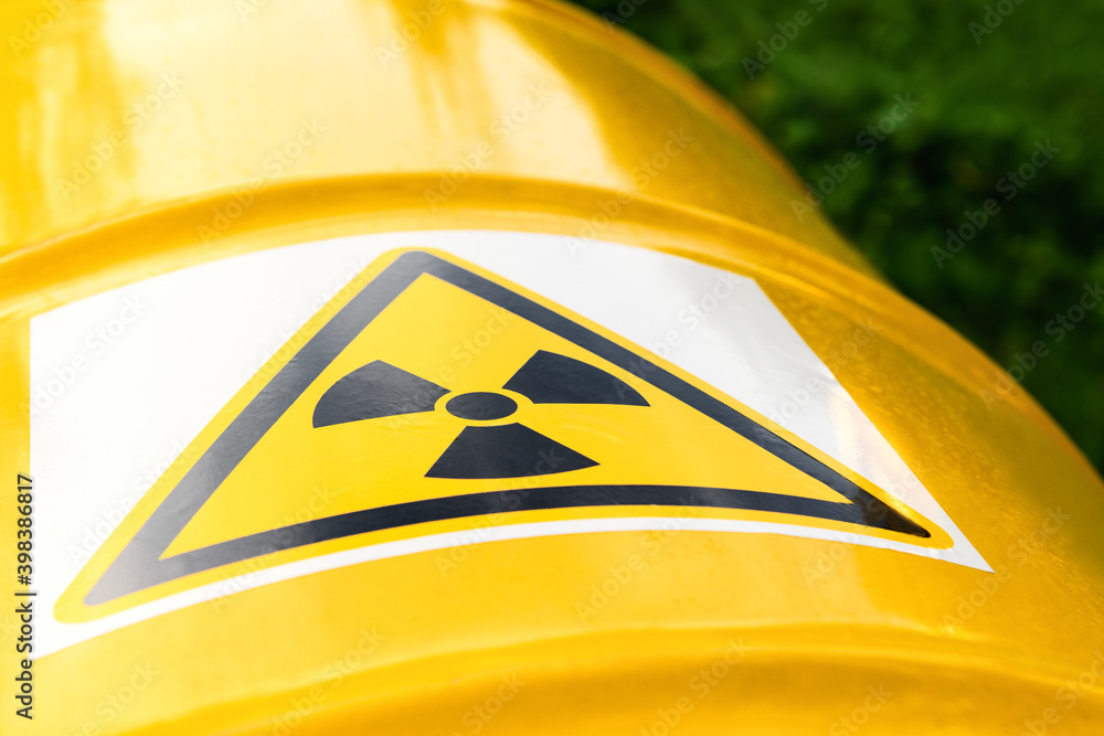 The nuclear sign on a yellow metal barrel on the green grass, close up ...