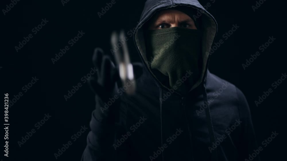 Vidéo Stock Robber in mask and hood rolling real gun on finger while ...