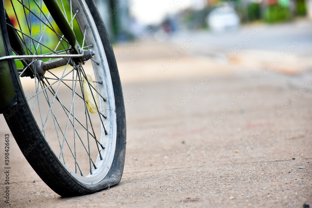 Rear wheel of bike which is flat and parked on the pavement beside the ...