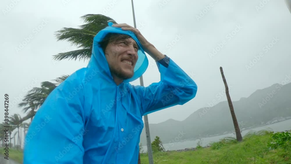 A man in a raincoat is under a hevy rain and stormy wind. Shot on an ...