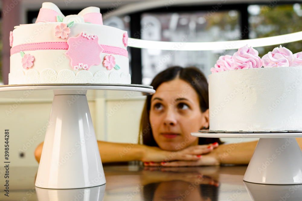 Woman sitting between two cakes. She has to make decision and she is ...