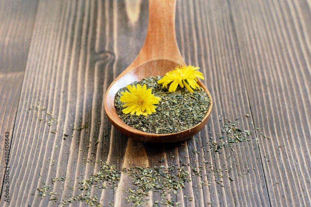 Wooden spoon with dandelions and dry flower tea close up. Eco friendly ...