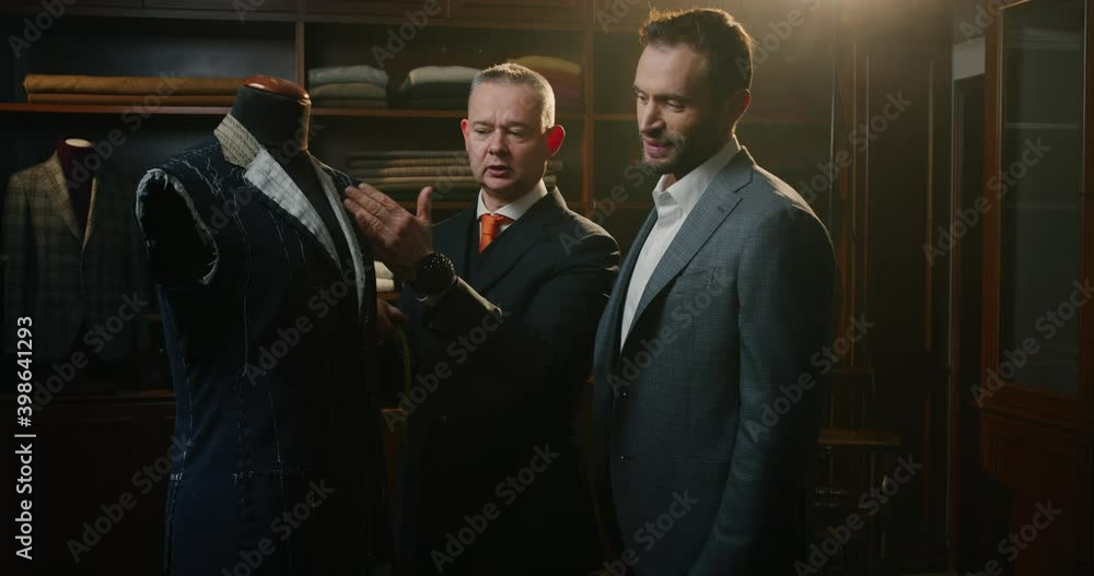 Cinematic shot of young handsome man is choosing design of suit with ...