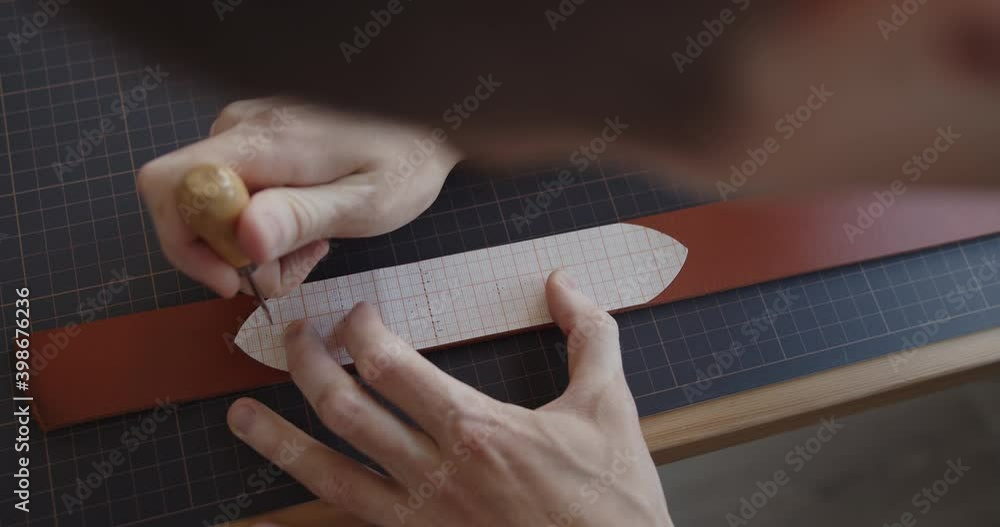 Making handmade leather belt. Young leather worker transfers the design ...