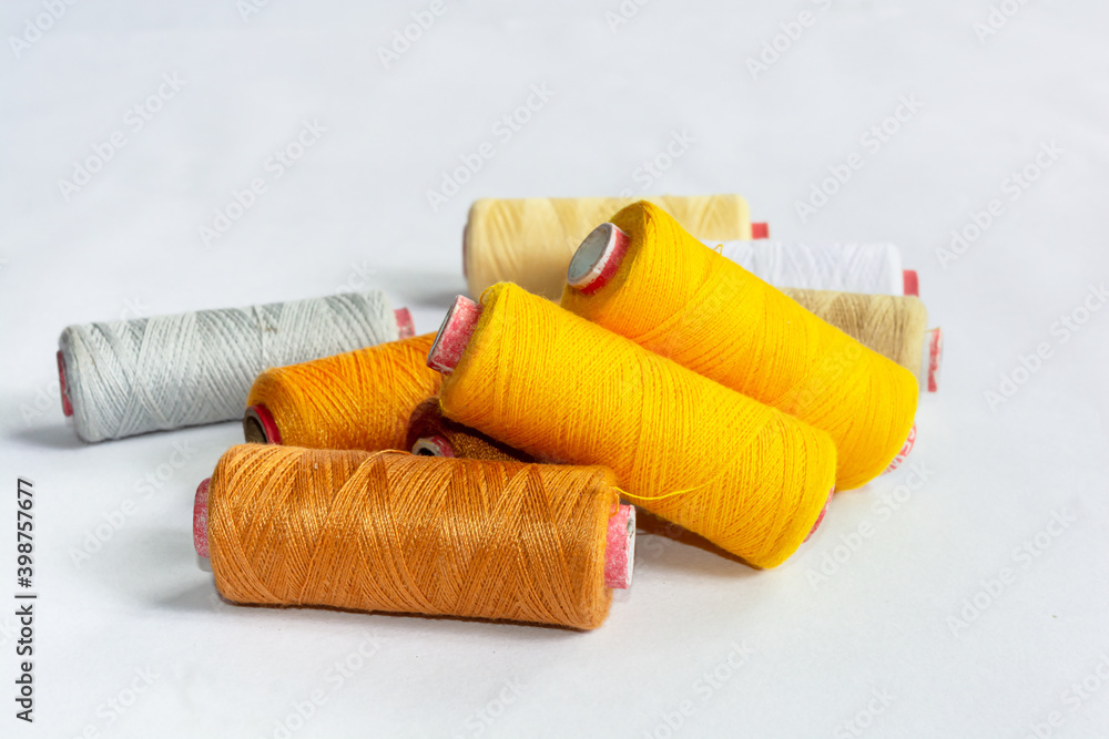 Different shades of yellow, brown, white and gray colored sewing thread ...