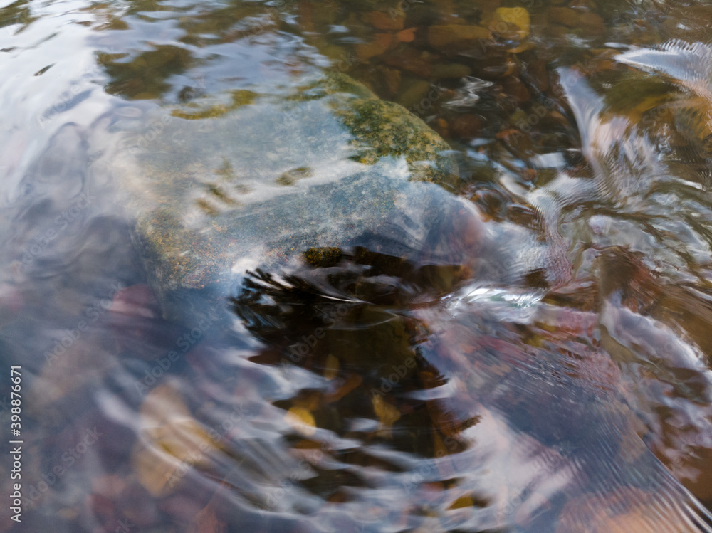 Wavy surface of water on shallow rapid stream with colorful gravel at ...