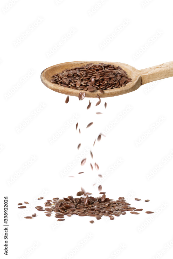 Linseed or flax seed falling from a wooden spoon into a small pile seen from the side and ...