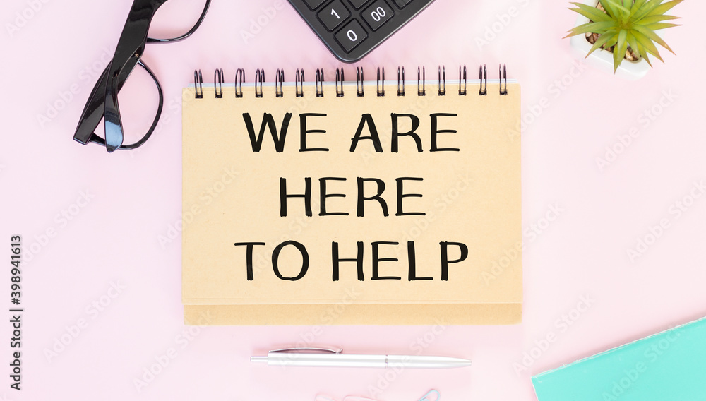 We are here to help, is written on a notepad, on an office desk with ...