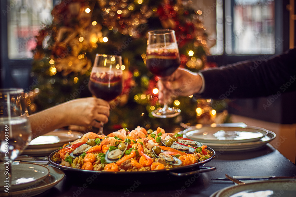 People sharing Spanish dinner table with assortment of dishes. paella ...